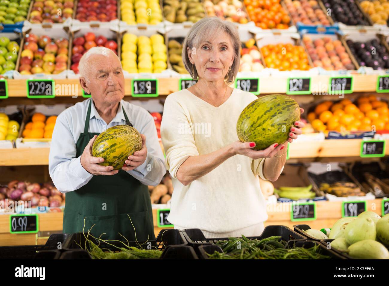 Grocery supermarket worker helping woman pick watermelon Stock Photo ...