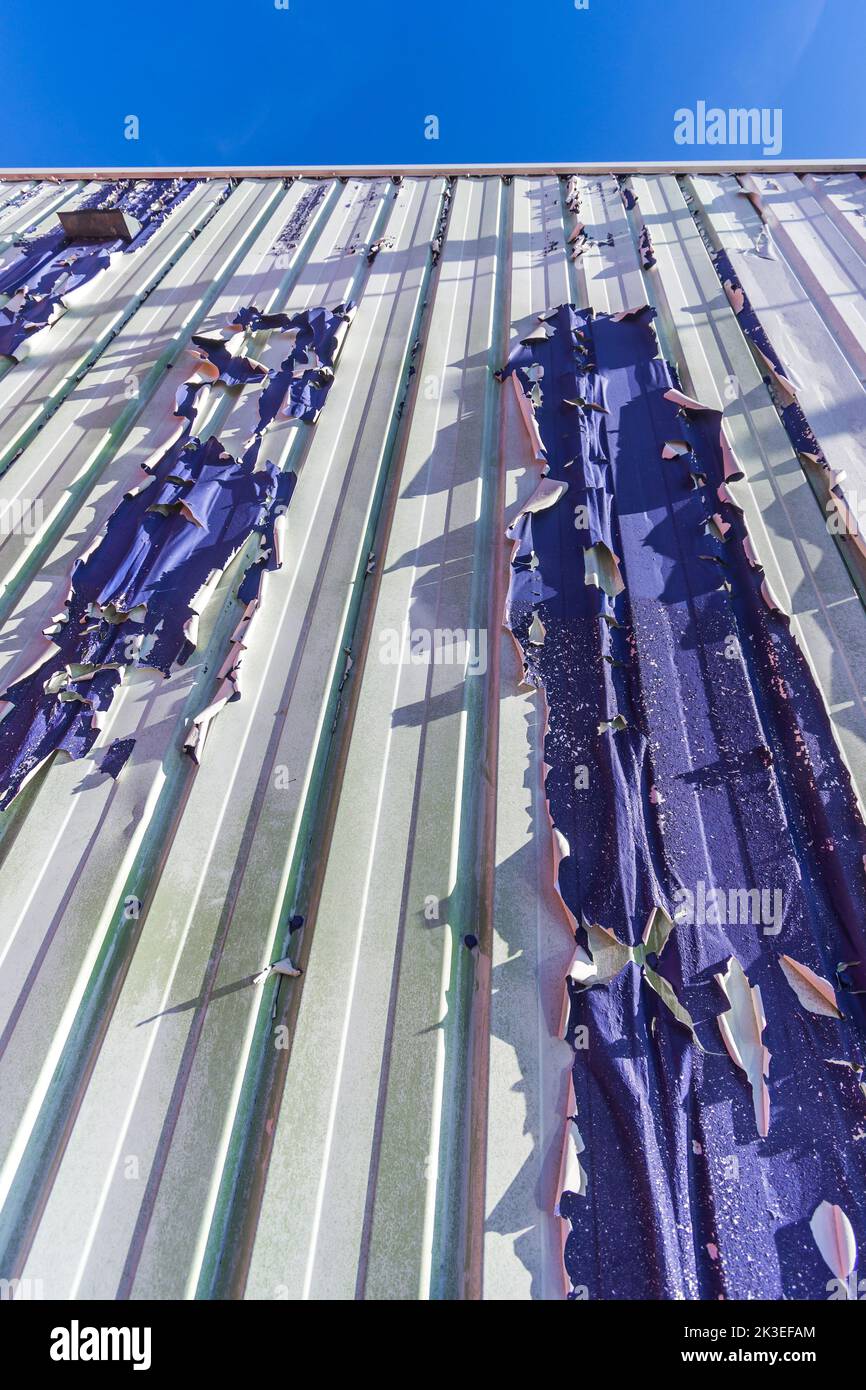 Badly peeling paint on metal cladding of modern building ...