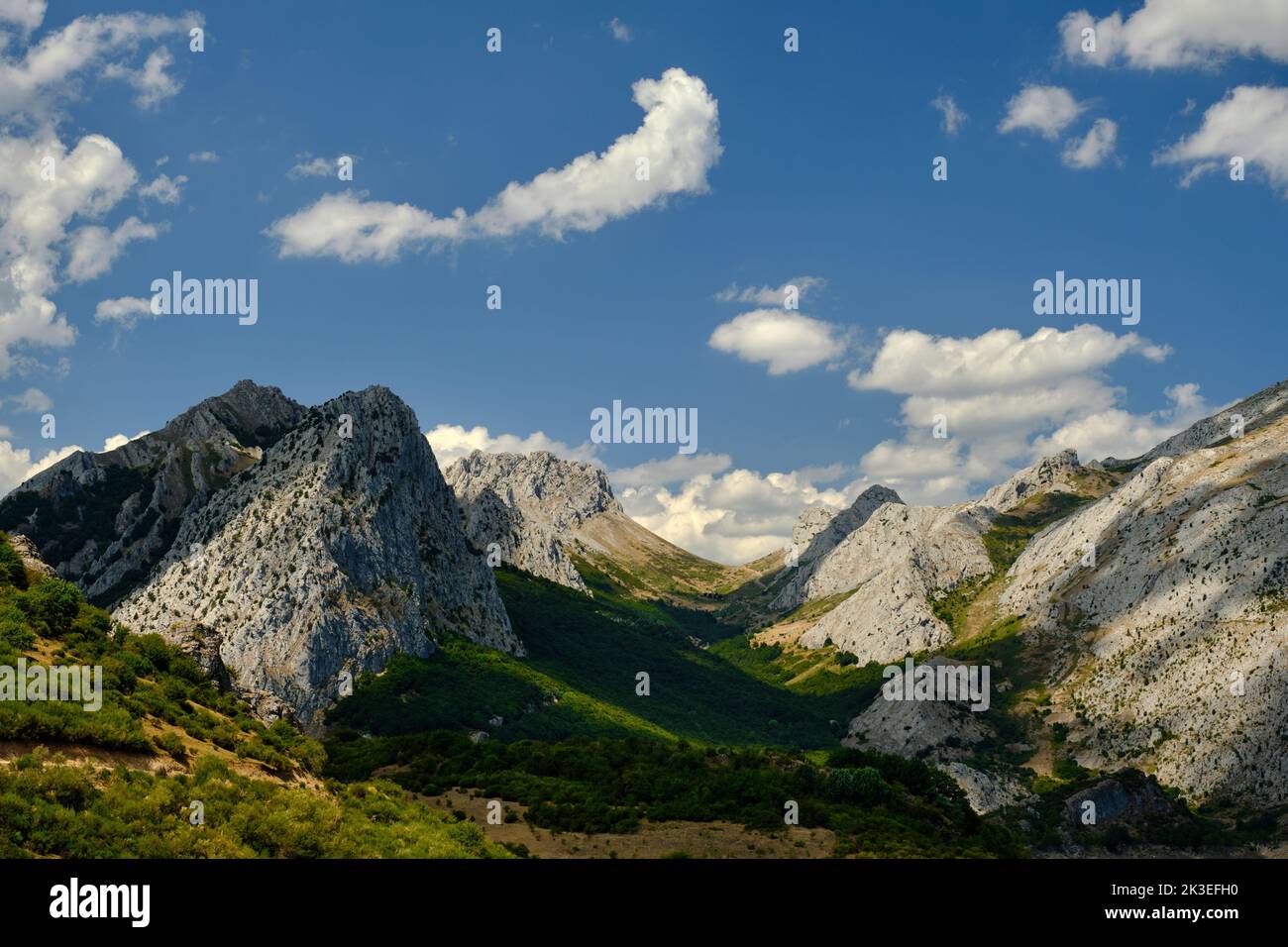 alpine landscape, rocky peaks under a blue sky, midday lights with ...
