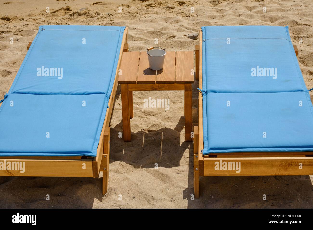 Closeup view of two blue sunbeds and a small table in front of the ...