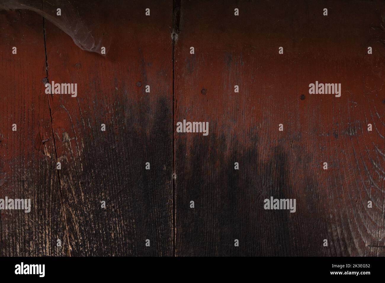 Wallboard background with weathered red paint with spider webs in the ...