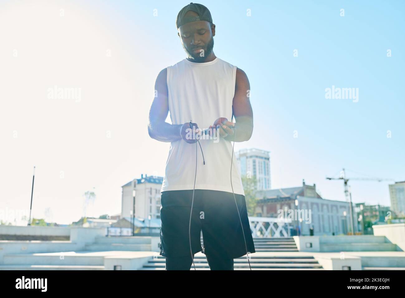 Young serene African American man in sportswear holding skipping rope ...