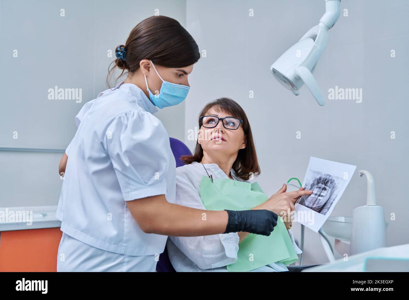 Female dentist talking to woman patient, discussing x-rays of teeth and ...