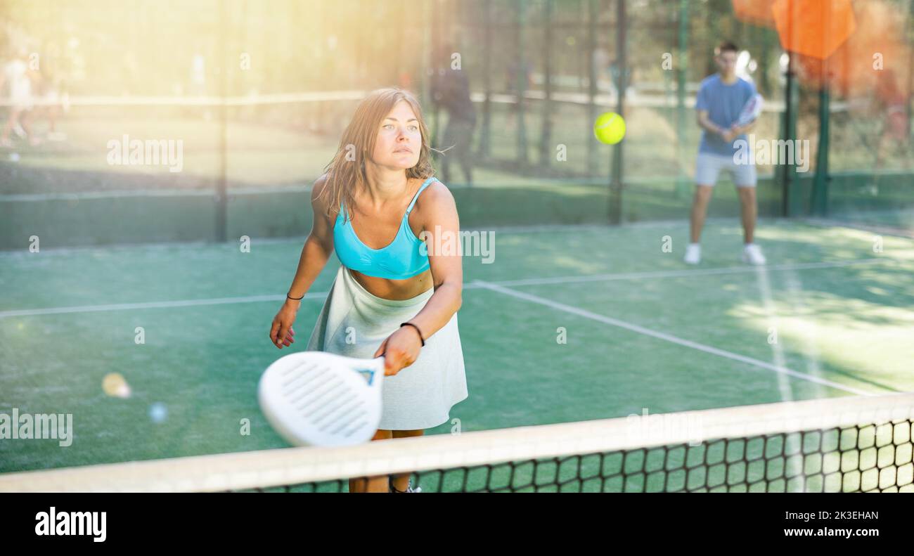 Training while playing on tennis court. Woman learning to play paddle ...