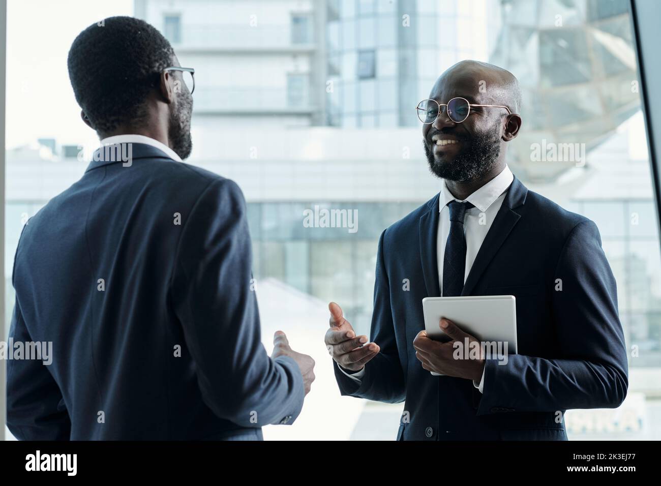Happy African American businessman with tablet talking to young male ...