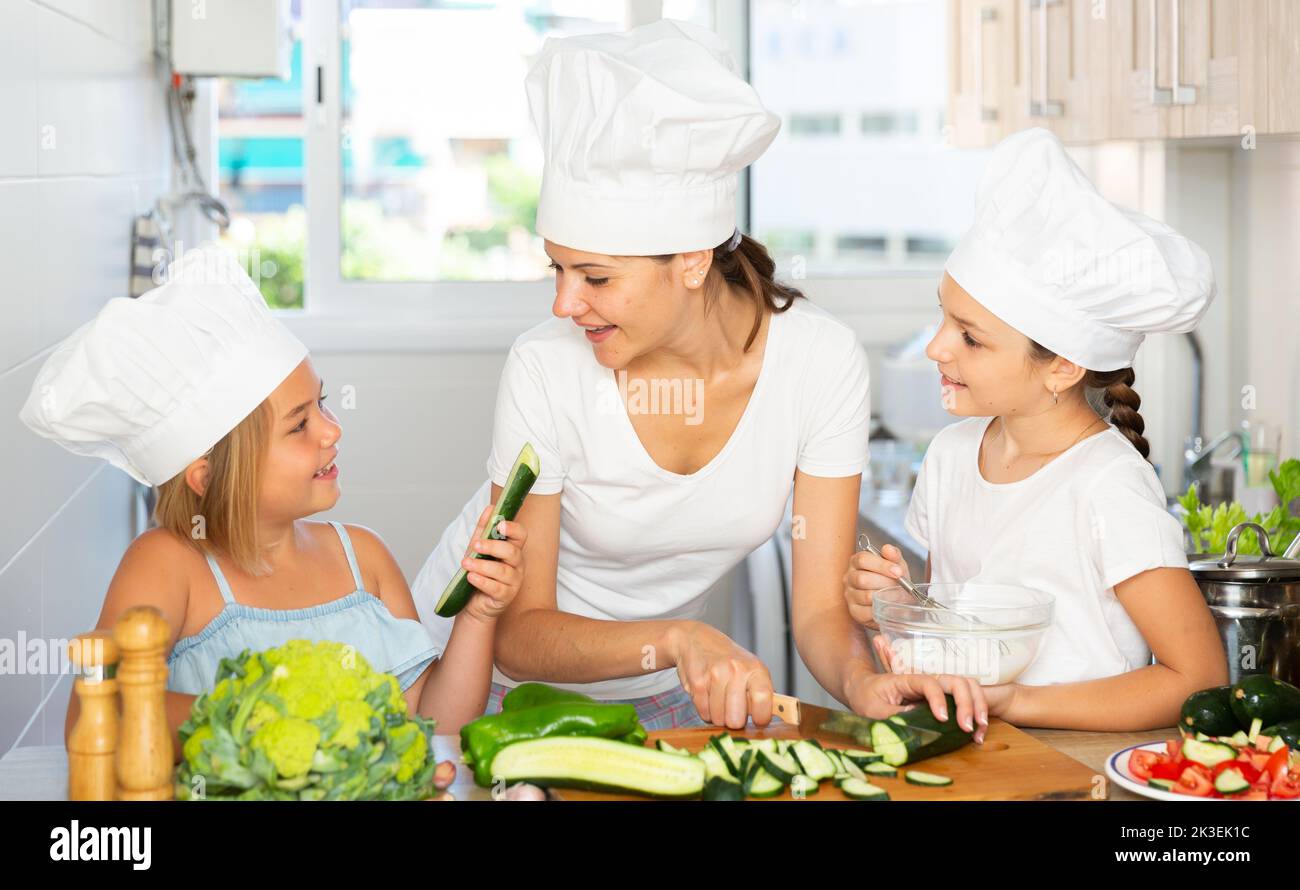 Little cooks learn with their mom how to cook a salad in the kitchen ...