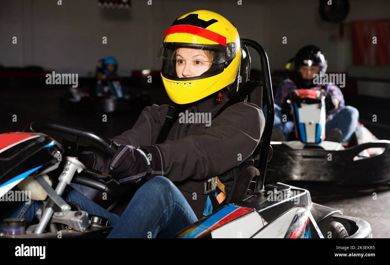 Girl and her friends competing on racing cars at kart circuit Stock ...