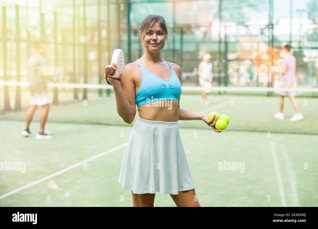 Positive girl looking at camera while playing padel at court Stock ...
