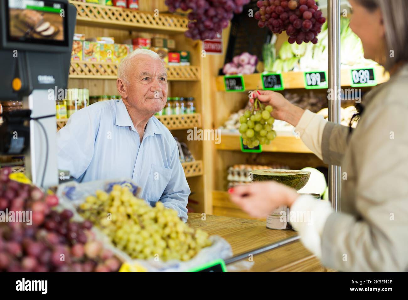 Senior salesman serving woman customer in greengrocer Stock Photo - Alamy