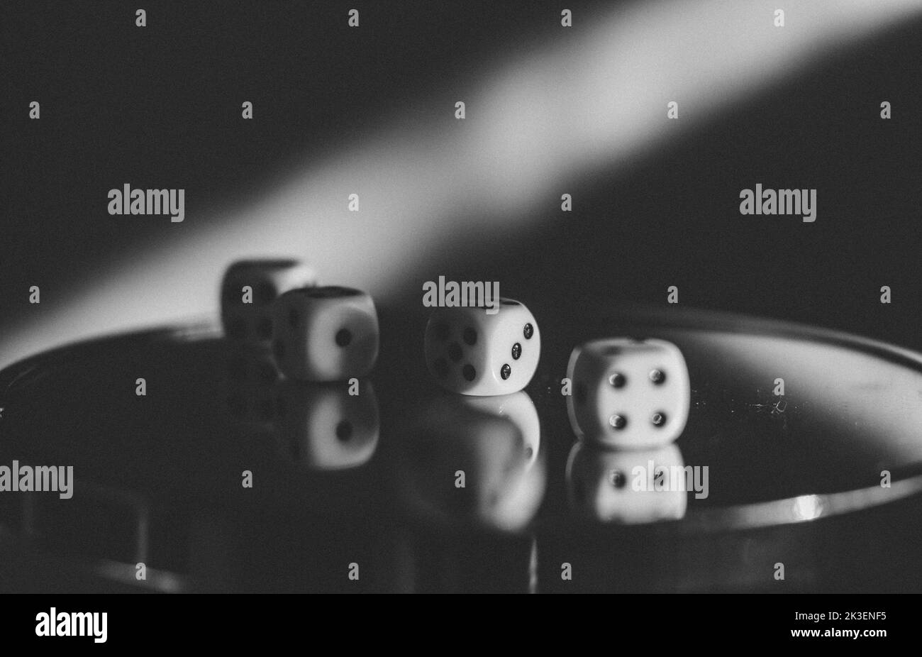 Playing dice on glass with reflections in it. Black and white photo ...