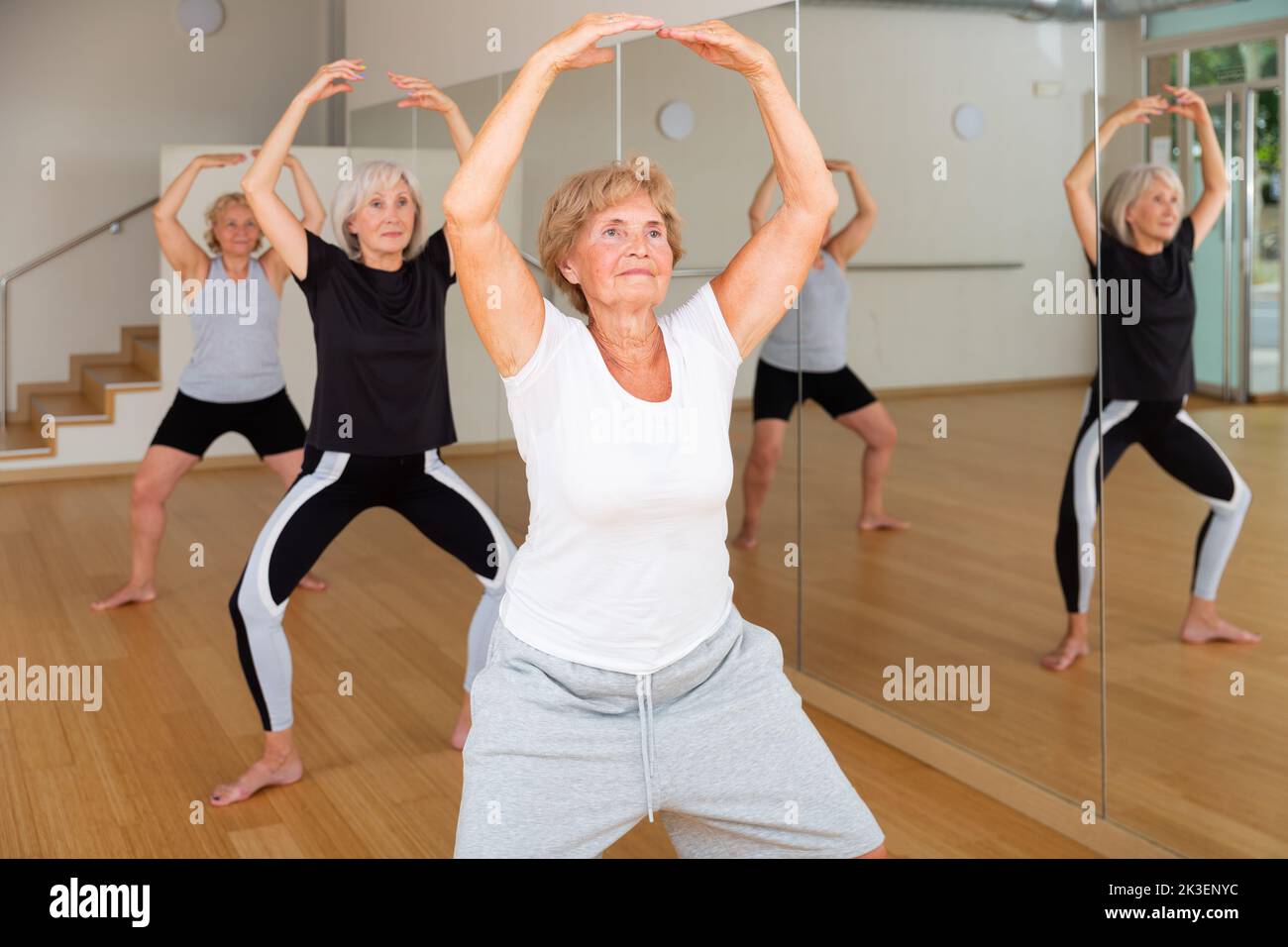 Mature women perform a plie squat while in the position of a ballet ...