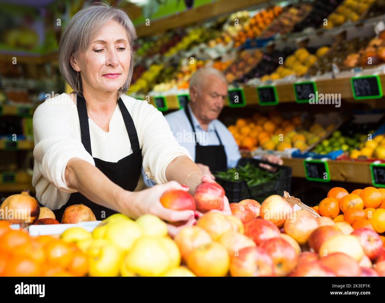 Female supermarket worker stacking fruits on shelf in sales room Stock ...