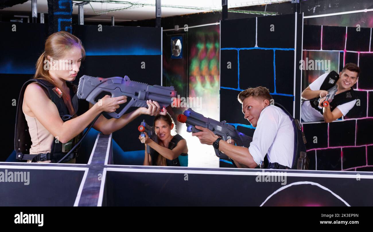 Laser tag players guys and girls playing in teams in dark laser tag ...