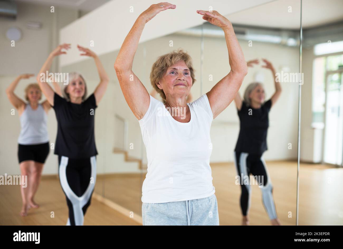 Senior lady learning classic dance moves during group class Stock Photo ...