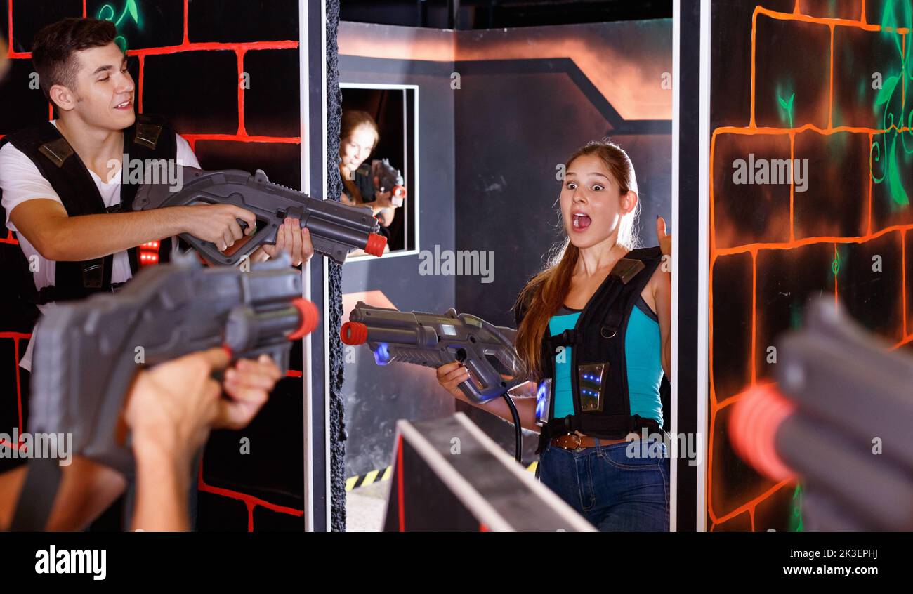 Laser tag players guys and girls playing in teams in dark laser tag ...