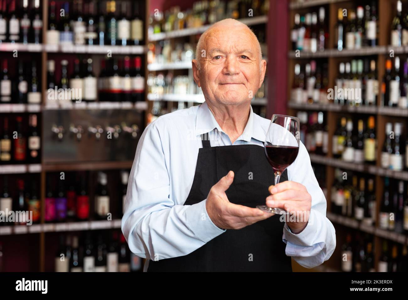 Successful elderly male owner of winery inviting to tasting wine of own ...