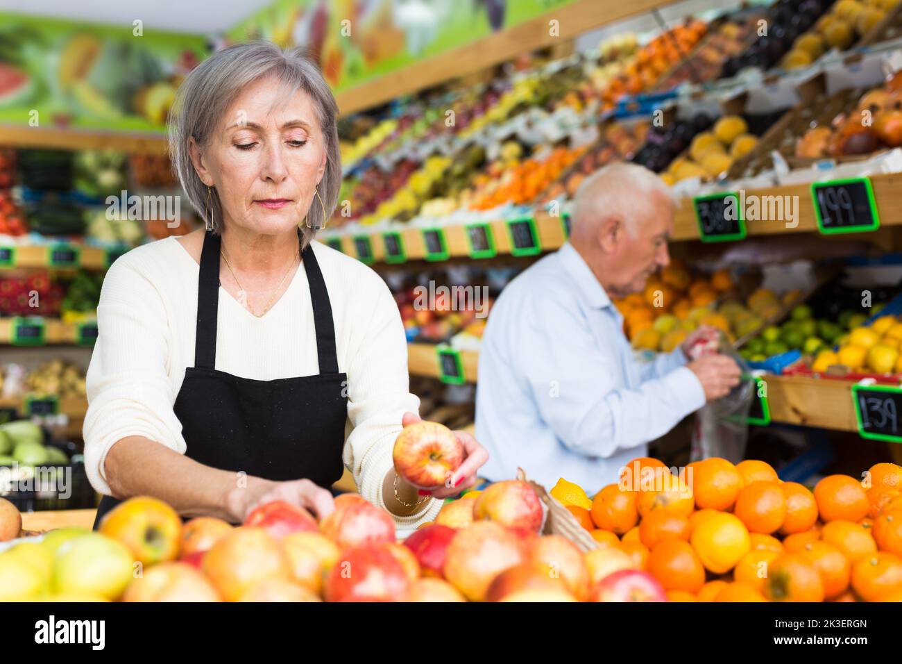 Lady greengrocer worker and old man customer in salesroom Stock Photo ...