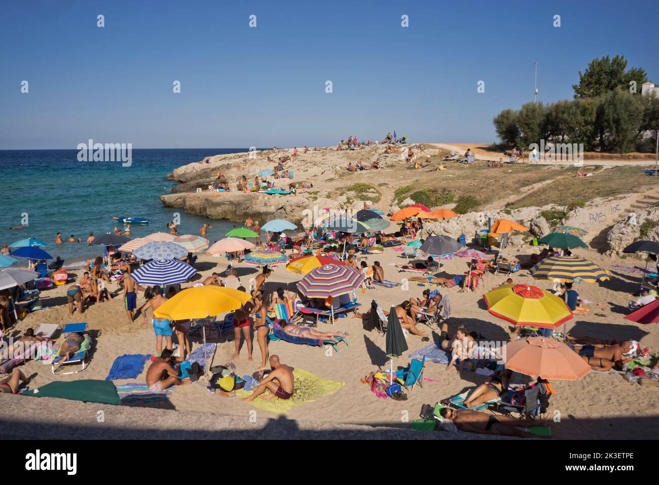 Local people and tourists at a beach by the old town of Monopoli ...