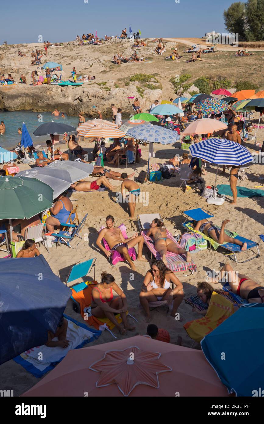 Local people and tourists at a beach by the old town of Monopoli ...
