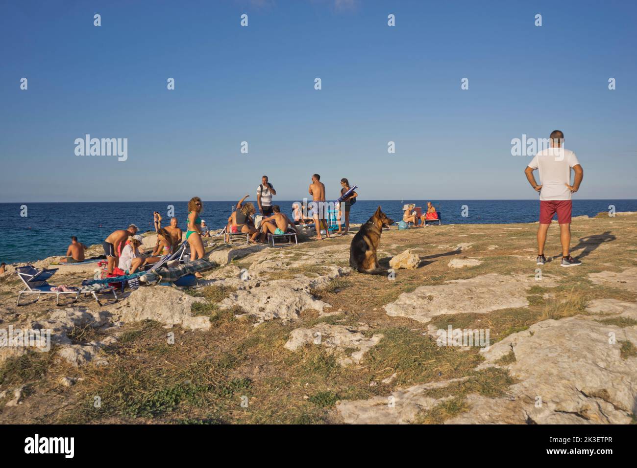 Local people and tourists at a beach by the old town of Monopoli ...