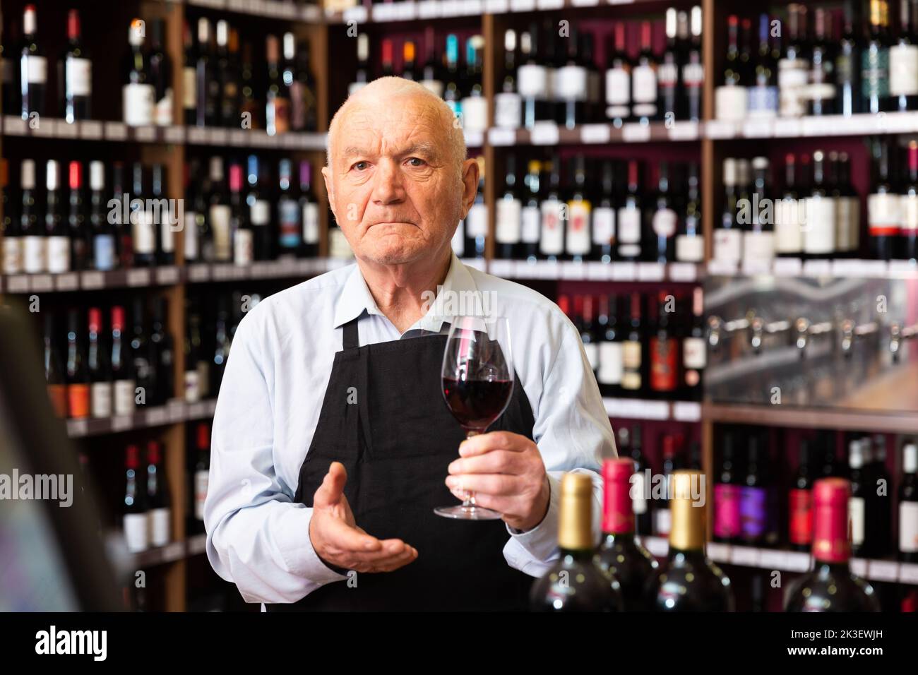 Successful elderly male owner of winery inviting to tasting wine of own ...