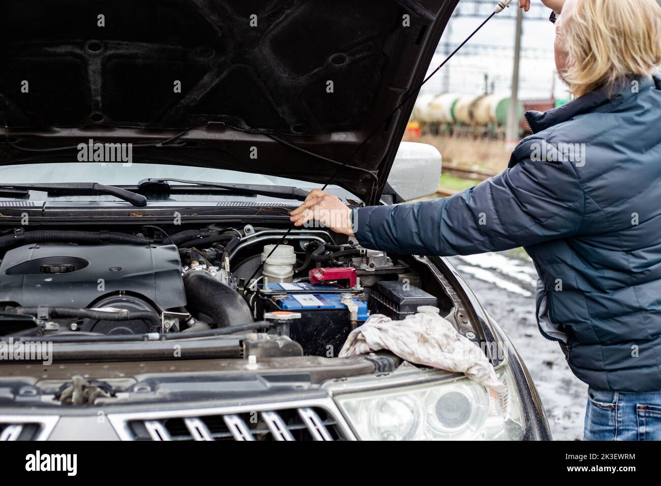 A man checks the oil level in a car engine with an iron dipstick ...