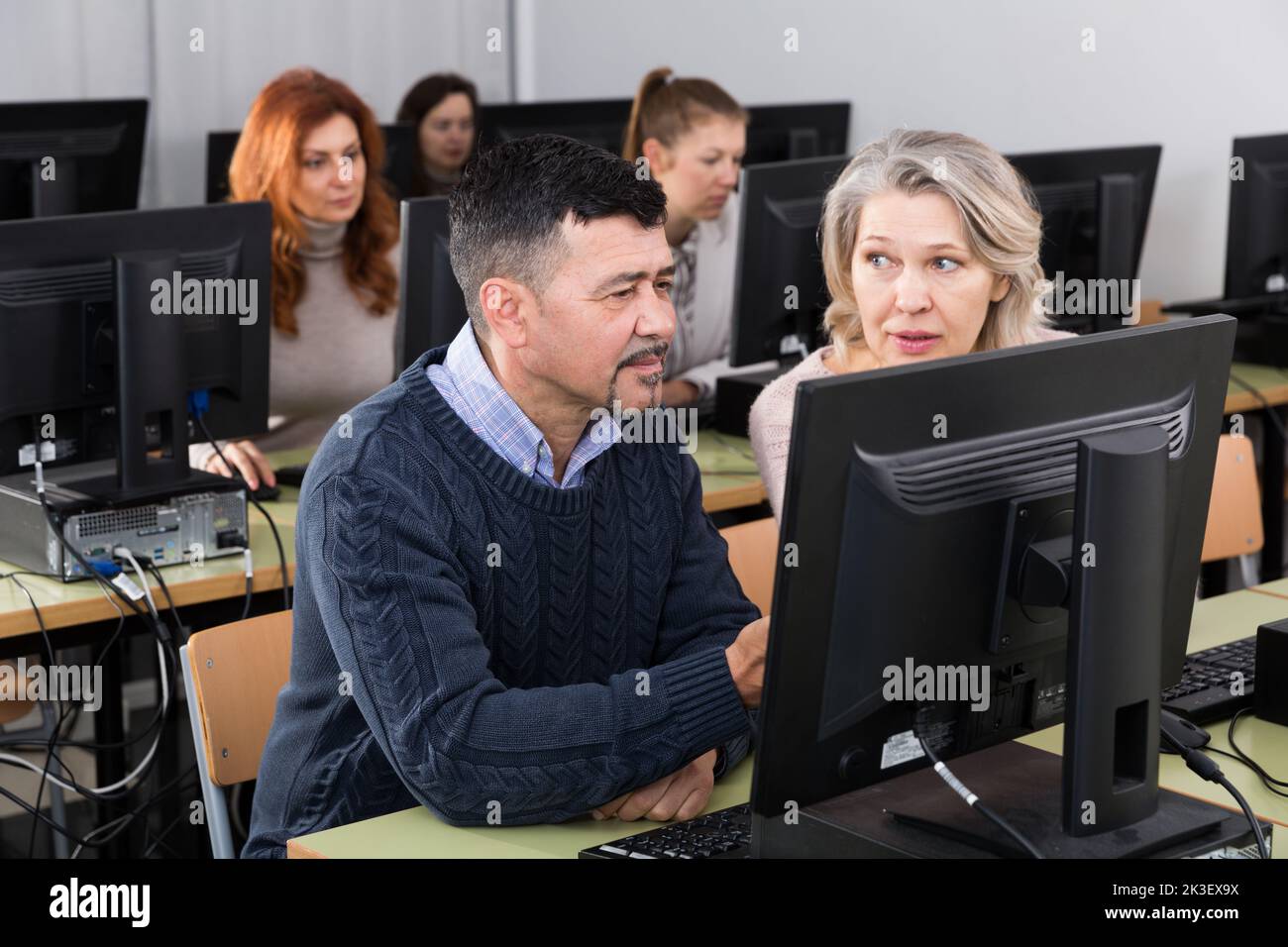 Middle aged man explaining computer skills for mature woman Stock Photo ...