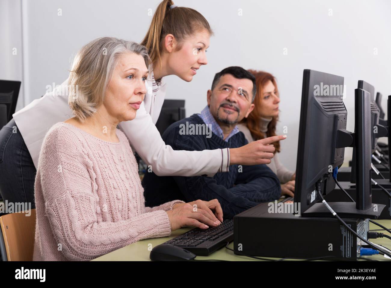 Serious businesswoman helping to man, pointing at computer monitor ...
