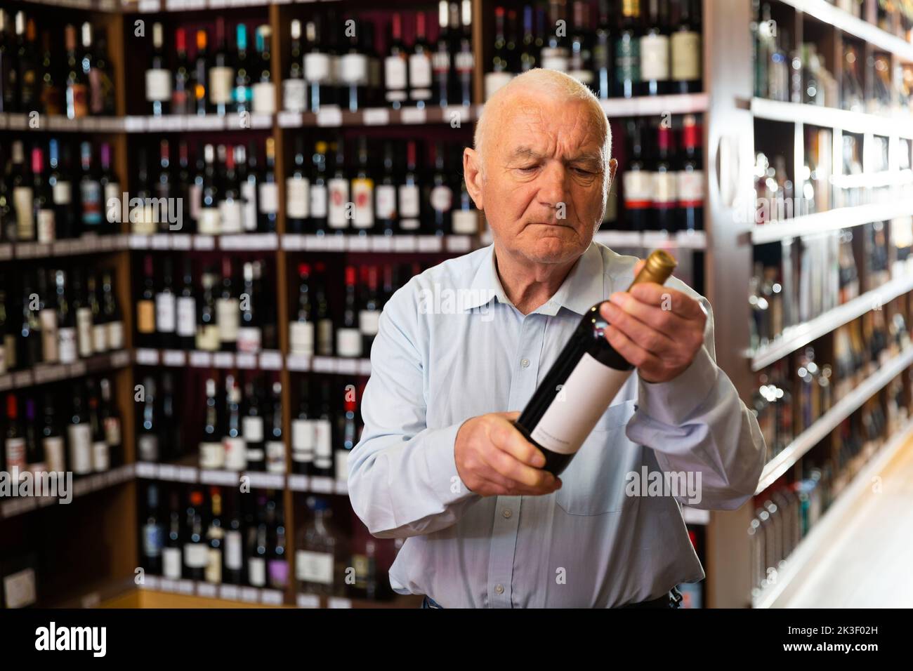 Elderly man chooses red wine in a liquor store Stock Photo - Alamy