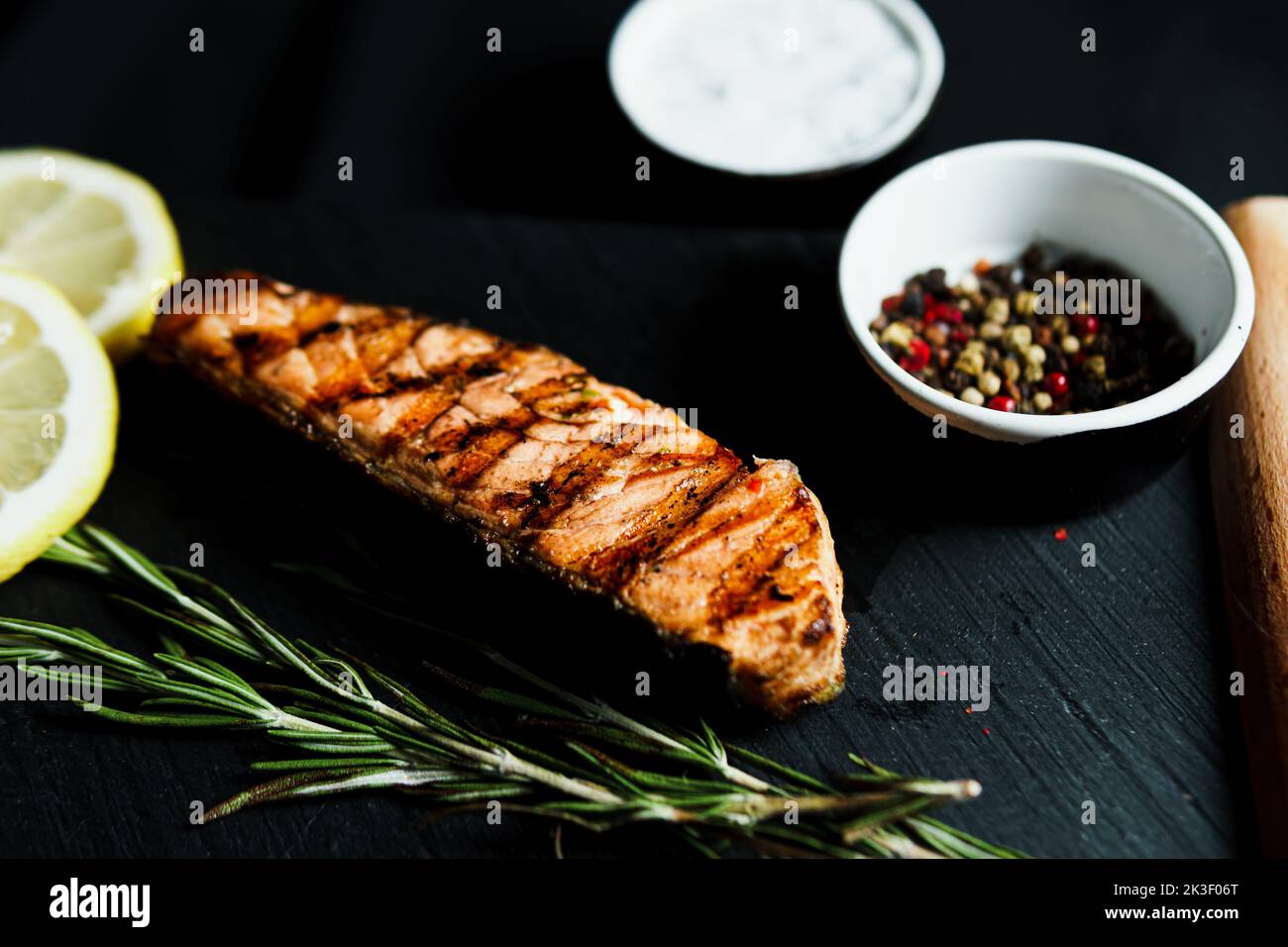 Grilled salmon fish fillet with green salad on the black cutting board ...