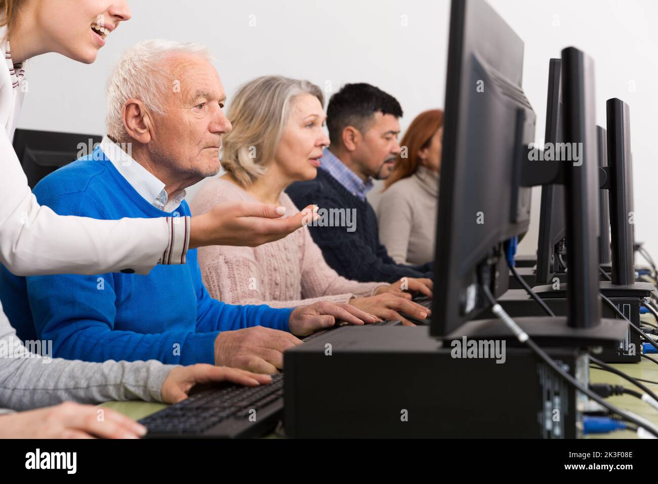 Serious businesswoman helping to man, pointing at computer monitor ...