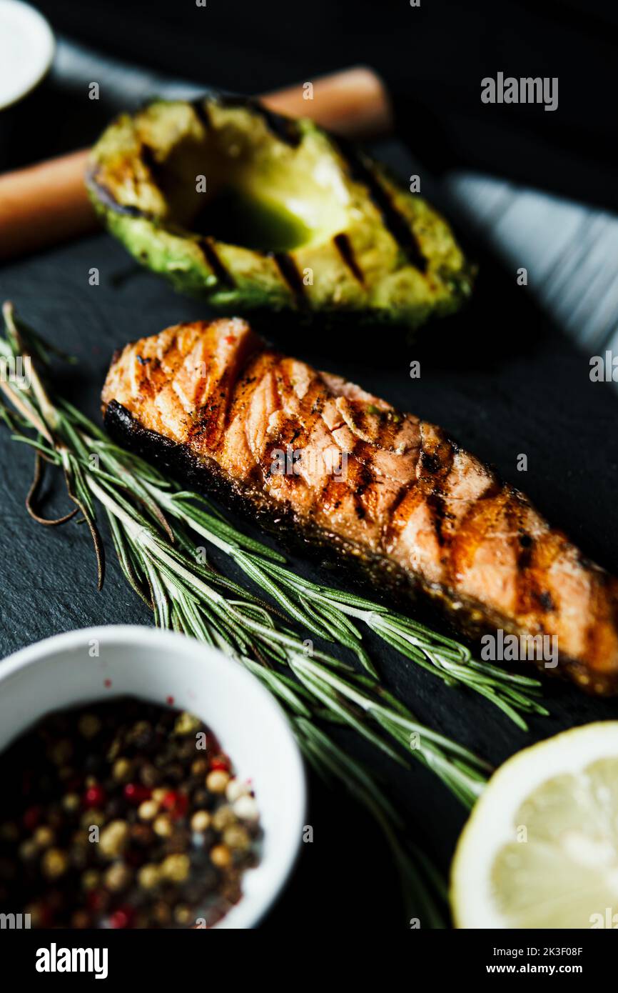 Grilled salmon fish fillet with green salad on the black cutting board ...
