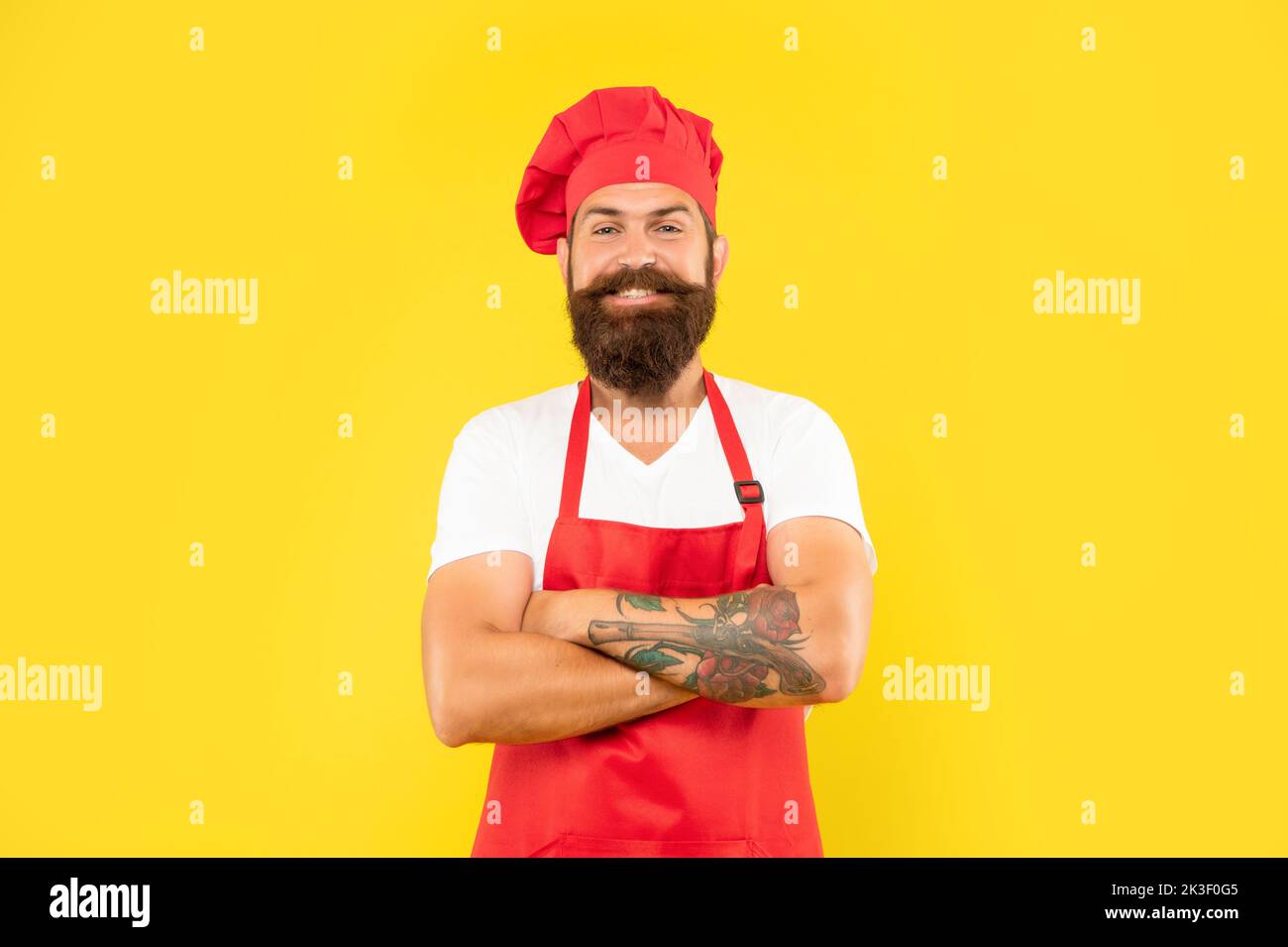 Happy man cook in red apron and toque keeping arms crossed yellow ...