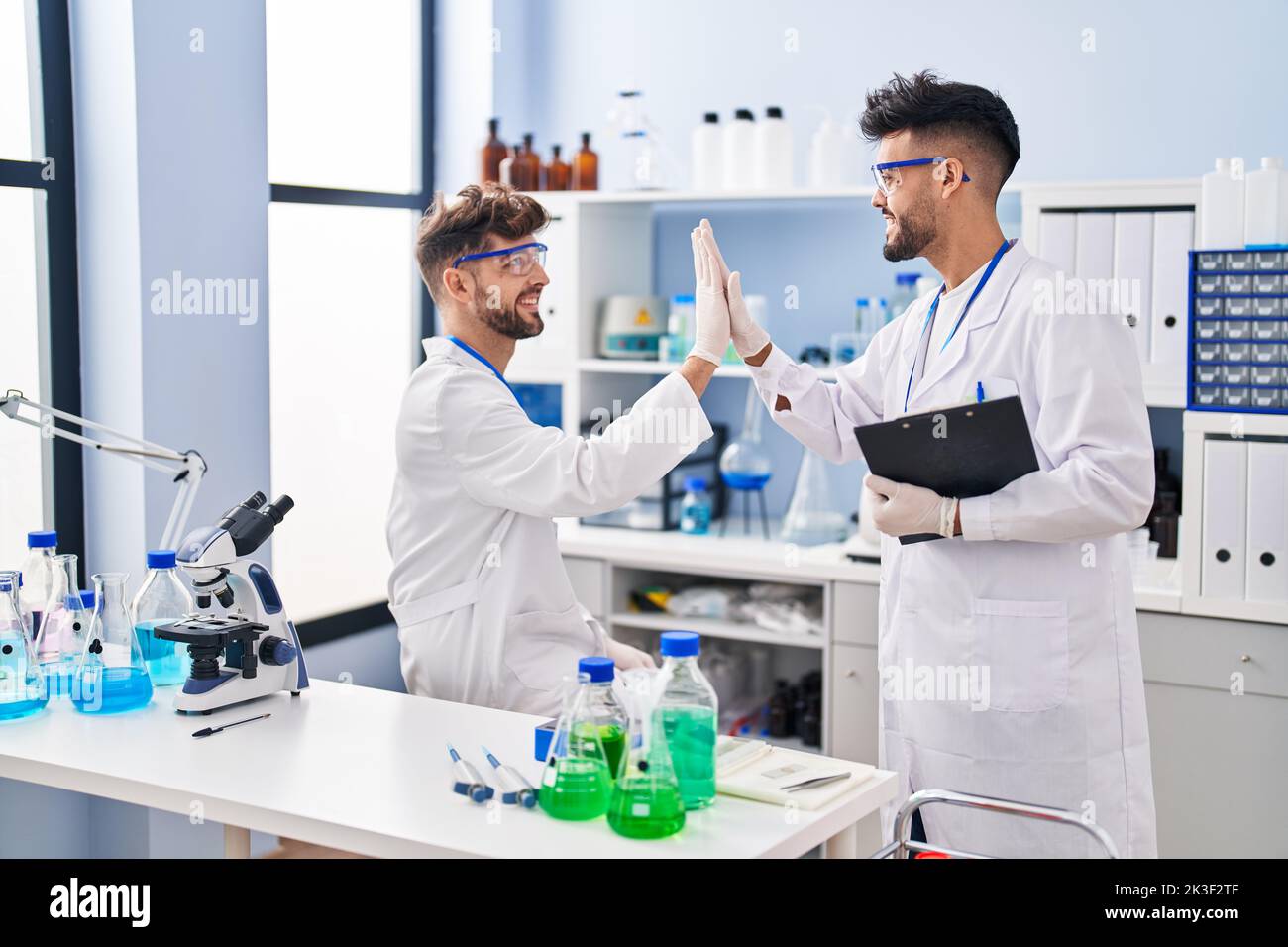 Young couple wearing scientist uniform using touchpad at laboratory ...