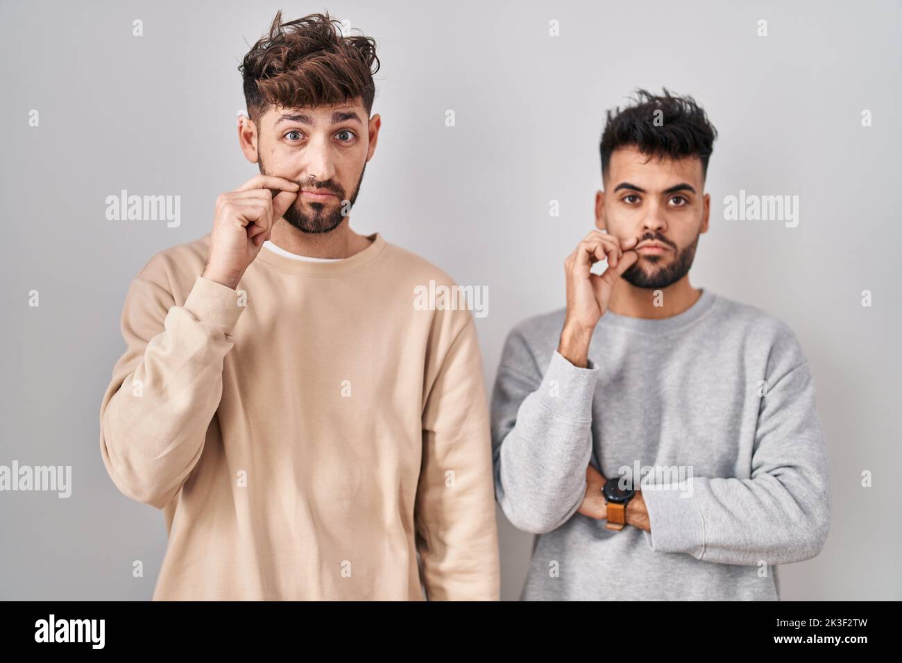 Young homosexual couple standing over white background mouth and lips ...