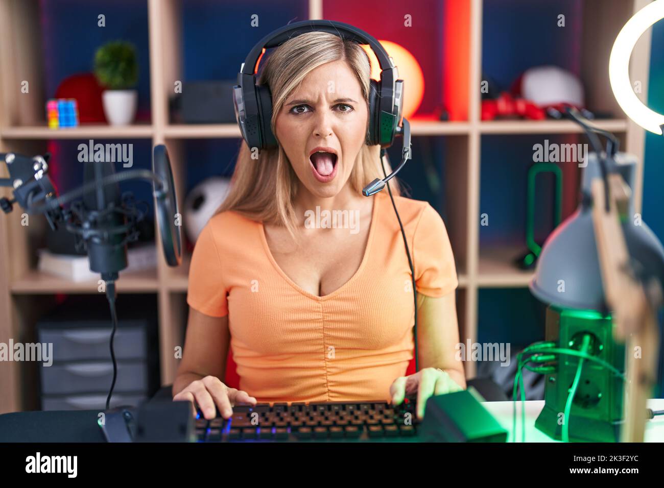 Young woman playing video games angry and mad screaming frustrated and ...