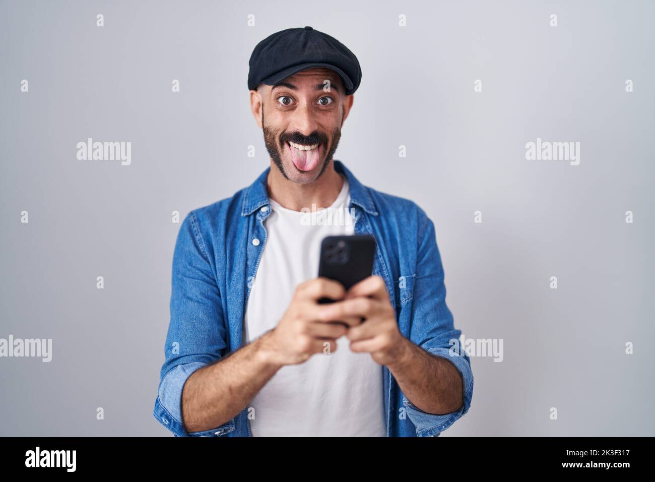 Hispanic Man With Beard Using Smartphone Typing Message Sticking Tongue