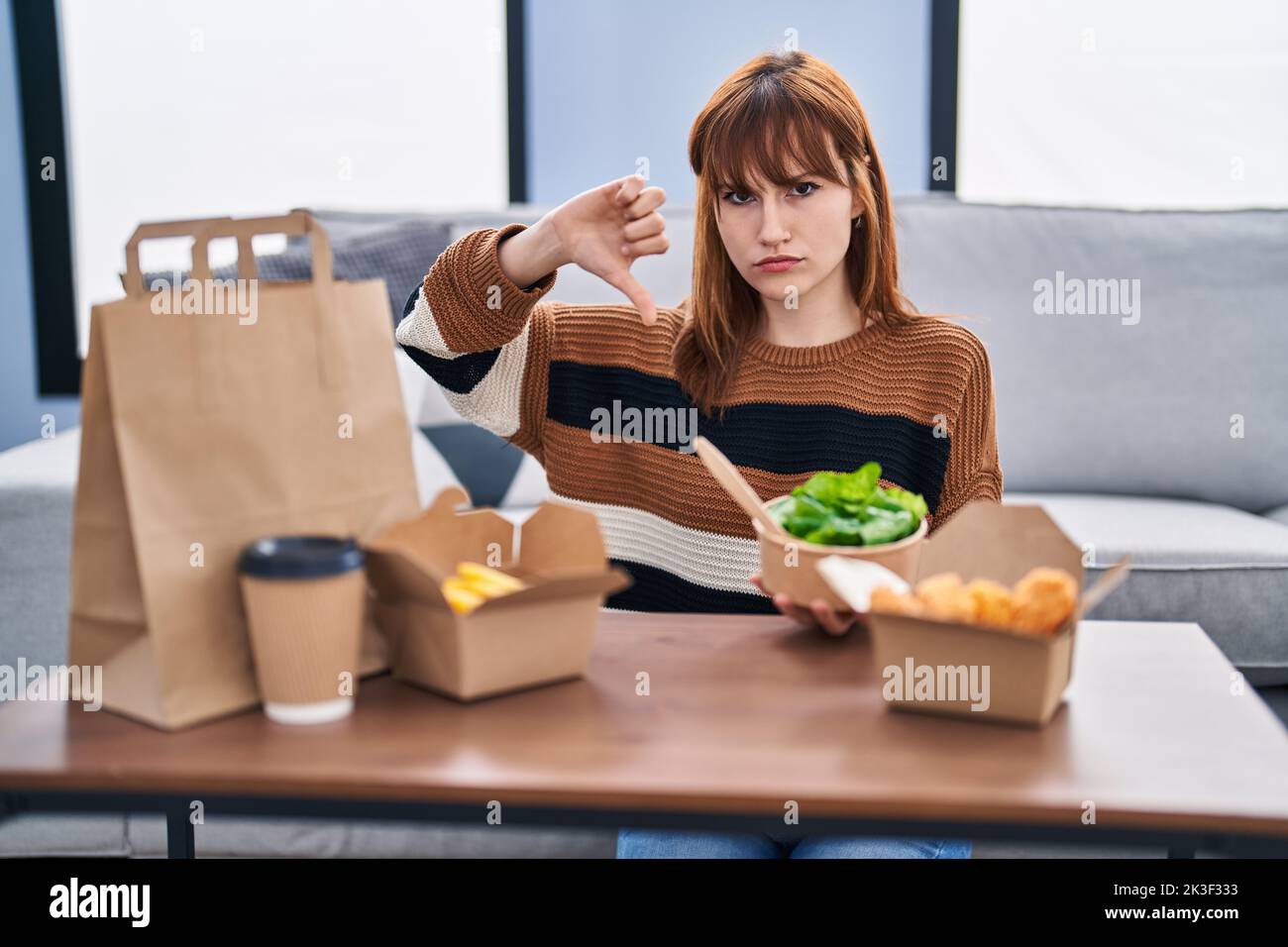 Young beautiful woman eating delivery food at the living room with ...