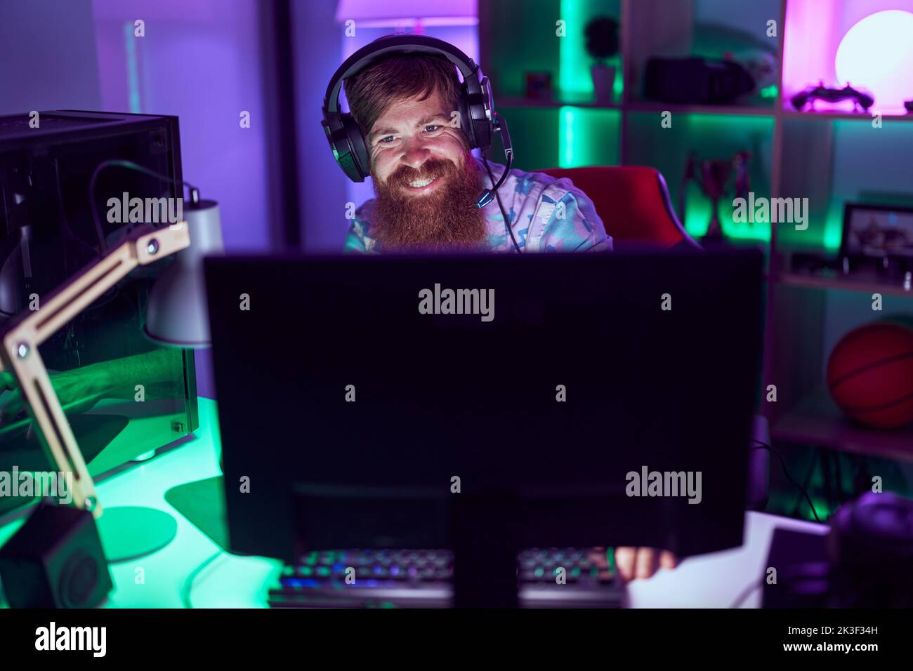 Young redhead man streamer playing video game using computer at gaming ...