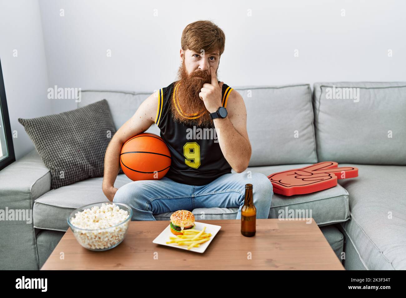 Caucasian man with long beard holding basketball ball cheering tv game ...
