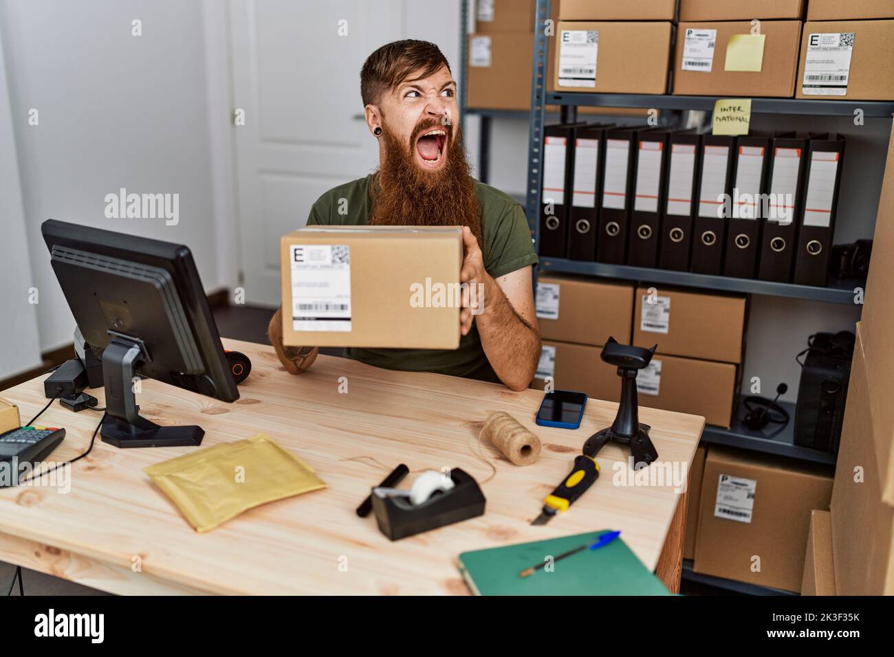 Redhead man with long beard working at small business ecommerce angry ...