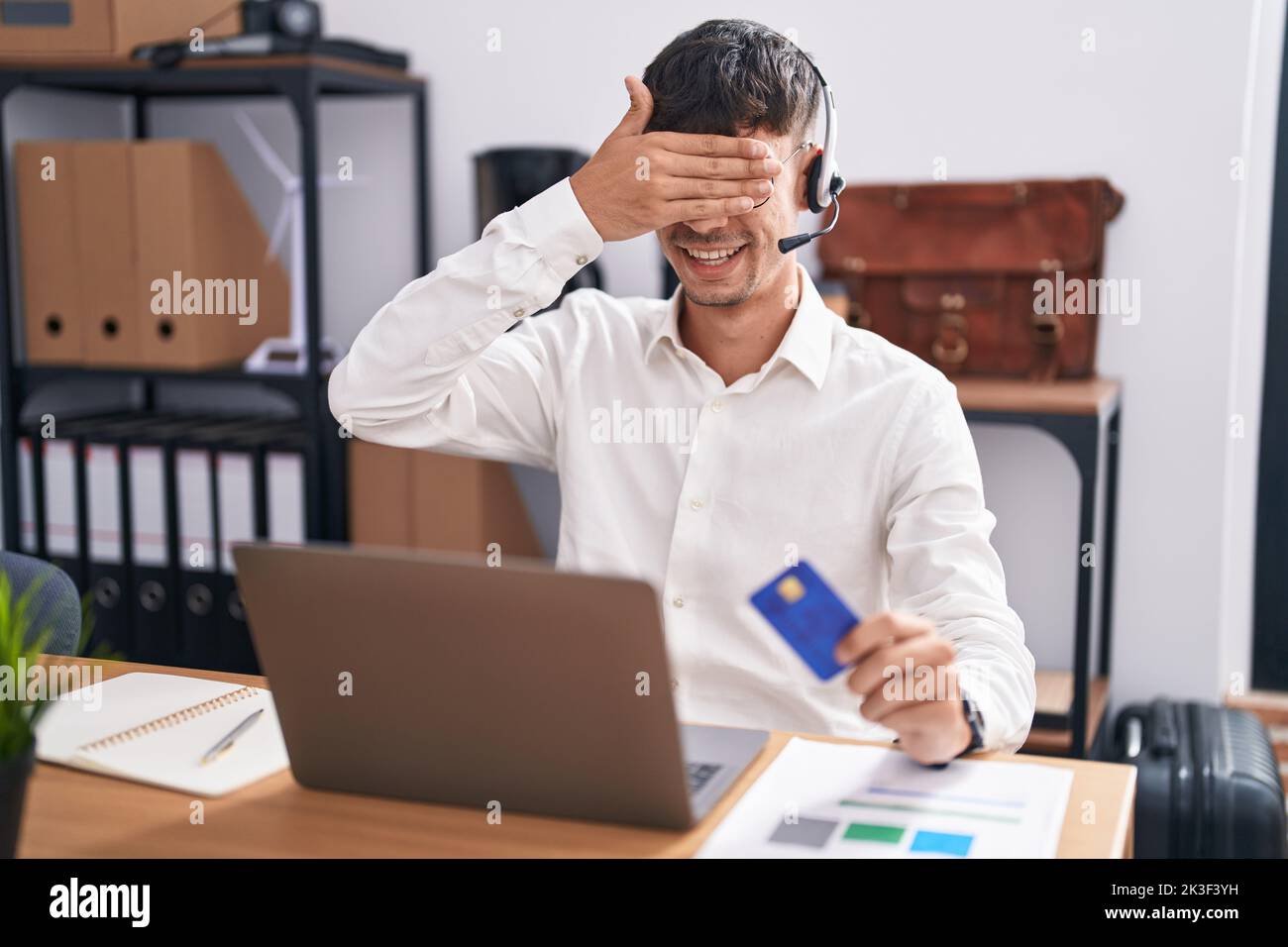 Young hispanic man working using computer laptop holding credit card ...