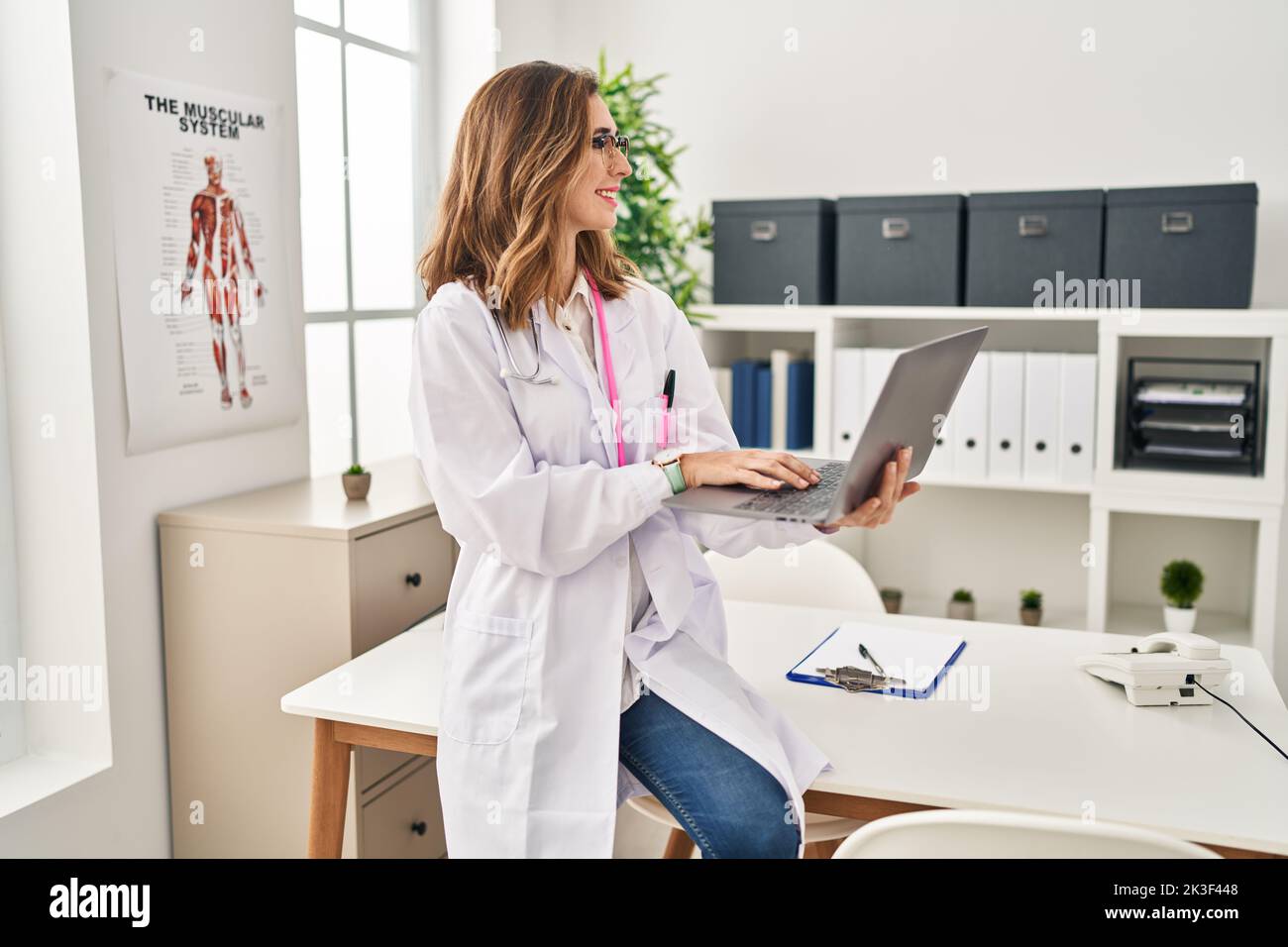 Young woman wearing doctor uniform using laptop at clinic Stock Photo ...