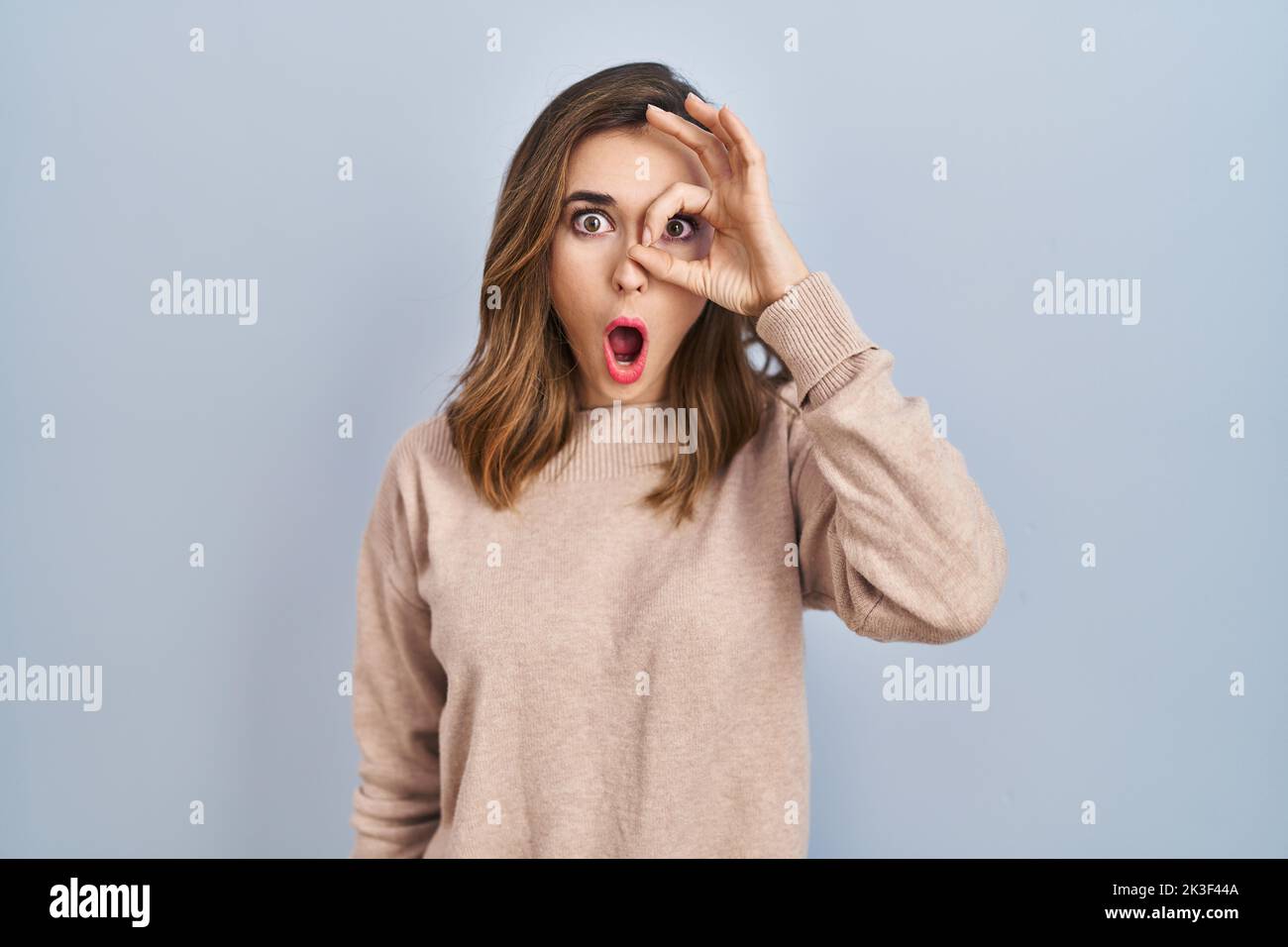 Young woman standing over isolated background doing ok gesture shocked ...