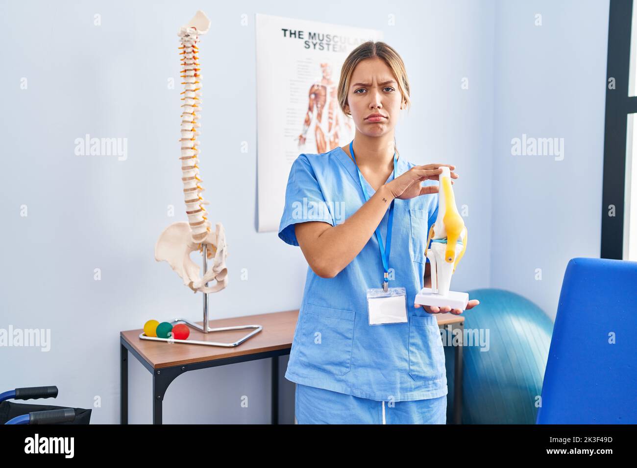 Young blonde orthopedic woman holding anatomical model of knee joint ...