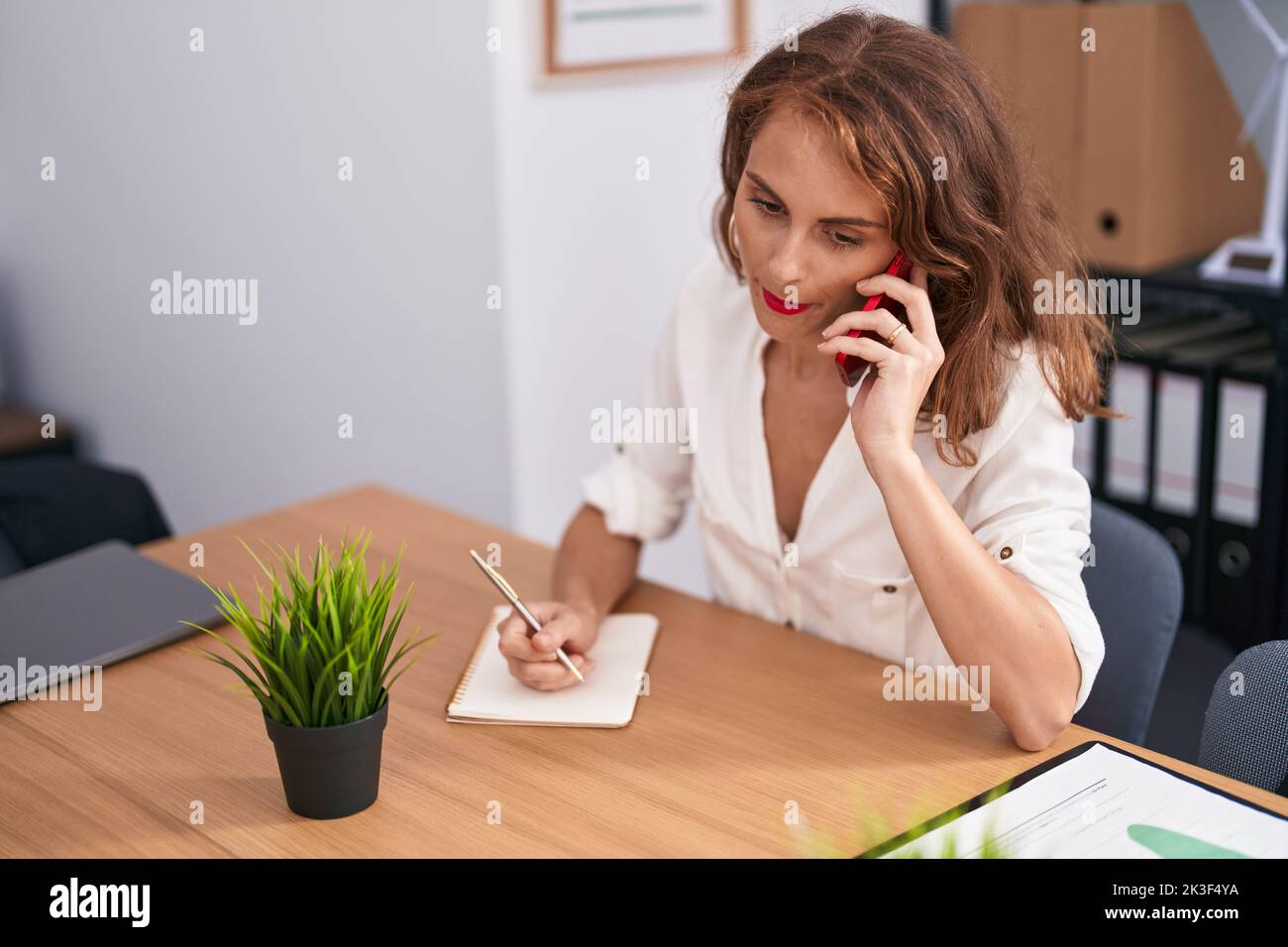 Young beautiful hispanic woman business worker talking on smartphone ...