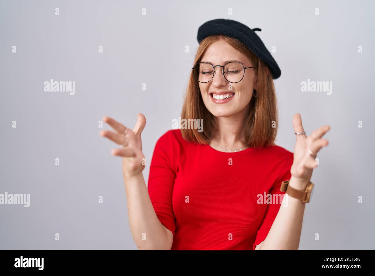 Young redhead woman standing wearing glasses and beret celebrating mad ...