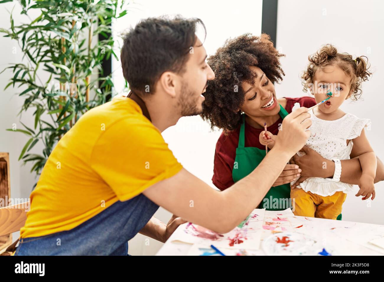 Couple and daughter smiling confident painting child nose at art studio ...