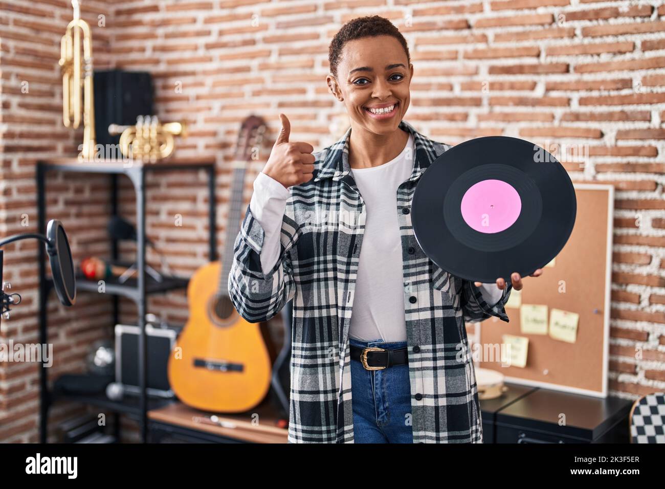 Beautiful african american woman holding vinyl record at music studio ...