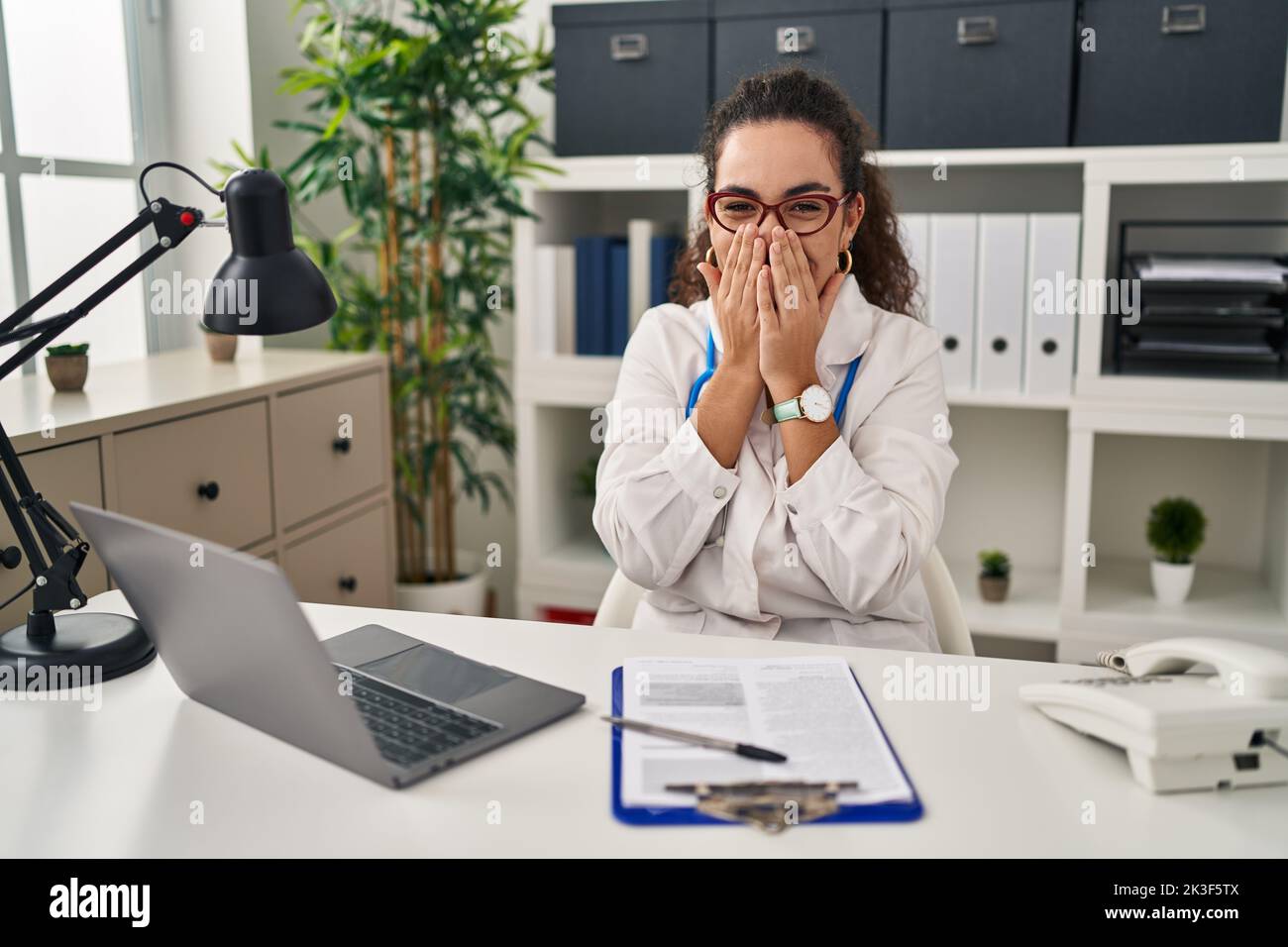 Young hispanic woman wearing doctor uniform and stethoscope laughing ...